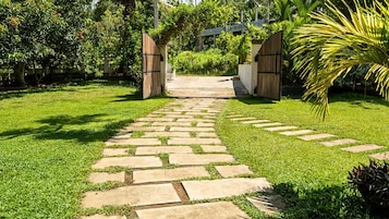 Um caminho de pedra leva a um portão de madeira em um jardim bem cuidado.