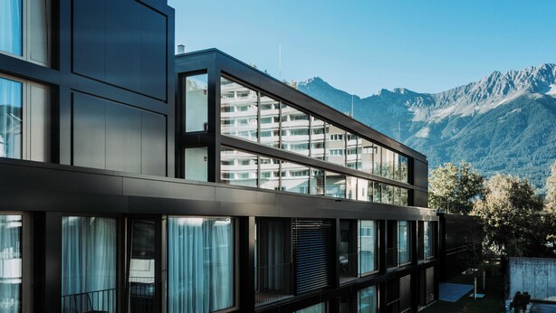 Um edifício moderno com grandes janelas e vista para uma cordilheira.