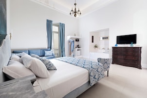 Um quarto moderno com uma cama grande, cômoda, televisão e um banheiro visível ao fundo.