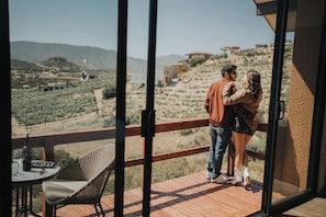 Um casal numa varanda com vista para um vinhedo.