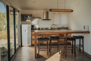 Cozinha moderna com ilha de madeira, banquetas e uma janela grande.