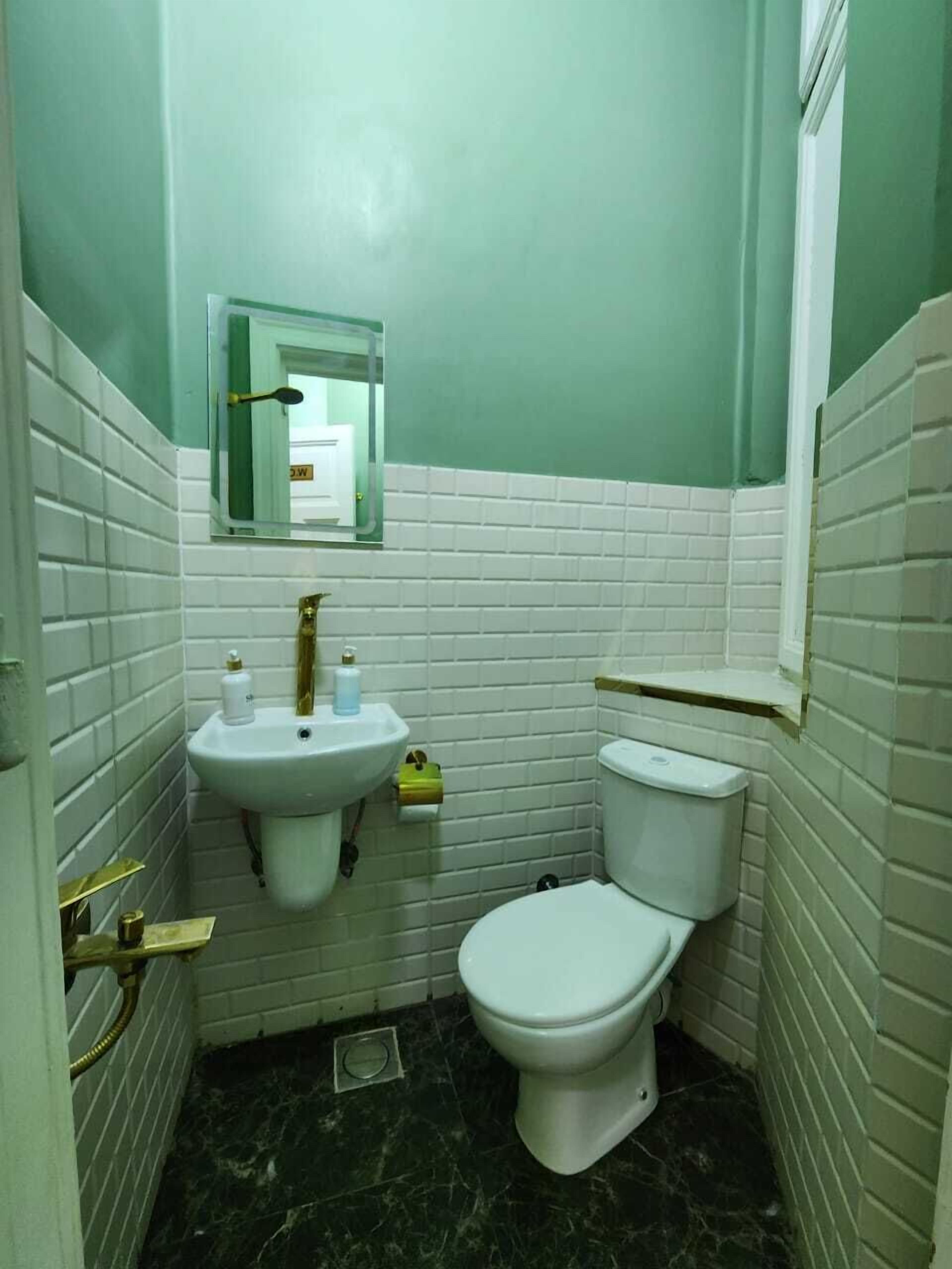 Um banheiro pequeno com pia branca, vaso sanitário e espelho.