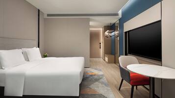 Quarto de hotel moderno com cama, televisão, escrivaninha e cadeira.