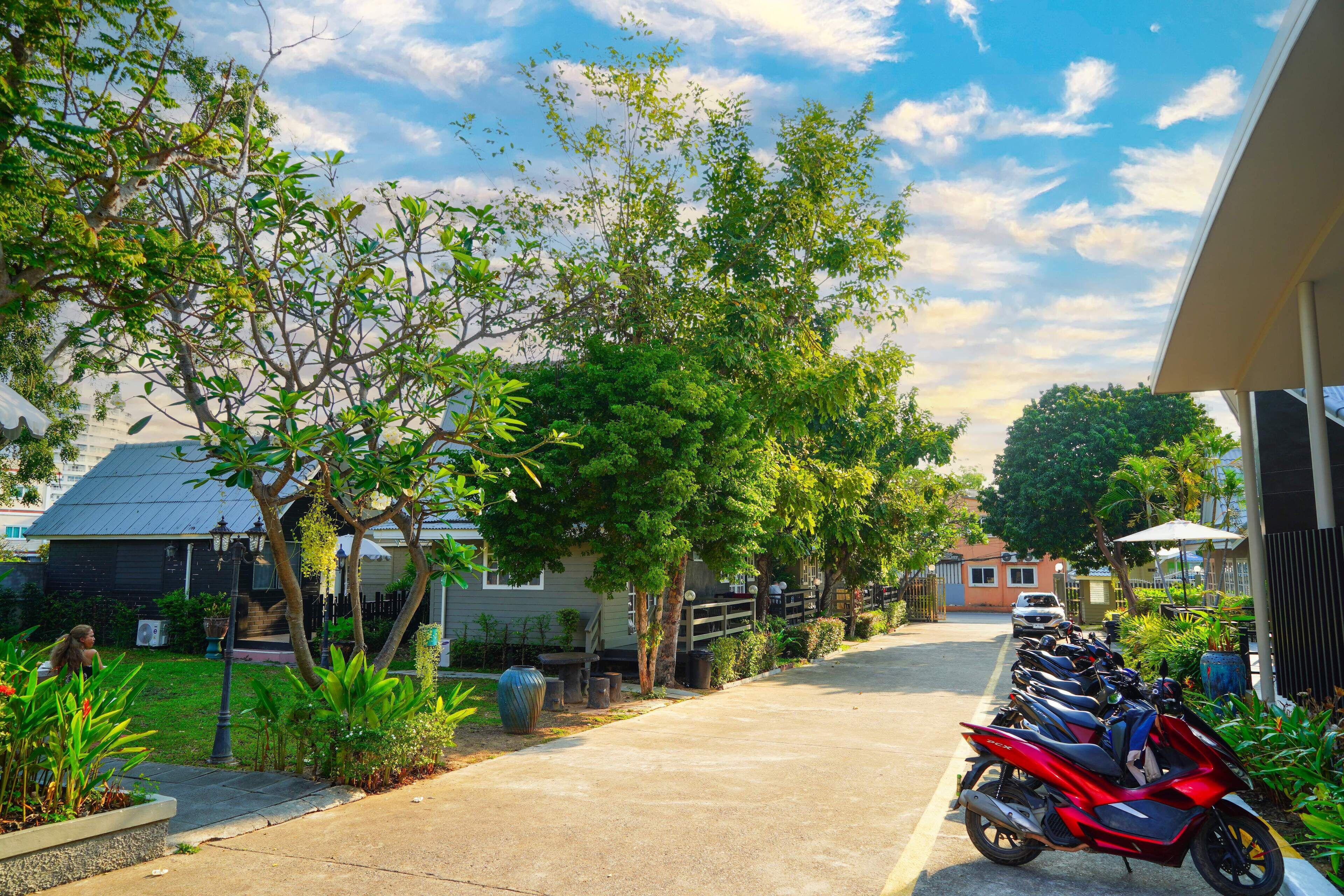 Rua residencial com motocicletas estacionadas, casas e vegetação exuberante.