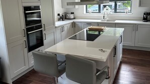 Cozinha moderna com ilha central, eletrodomésticos de aço inoxidável e uma ampla janela que traz luz natural.