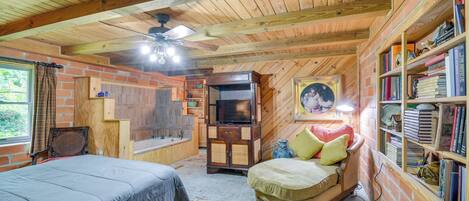 Um quarto rústico com uma cama, um sofá, uma televisão e uma estante de livros.