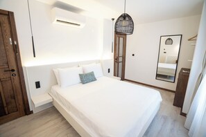 Quarto com uma cama grande, um guarda-roupa de madeira, uma luminária pendente e um espelho na parede.