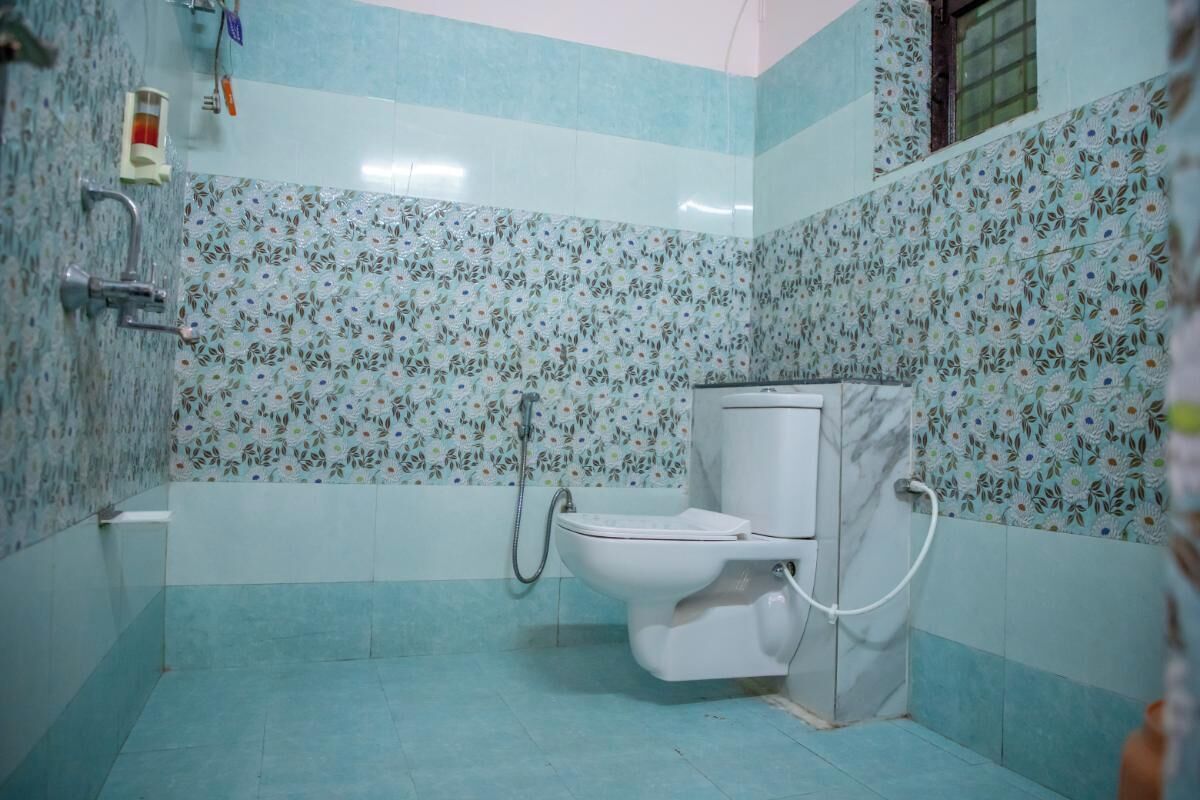 Casa de banho pequena com sanita, chuveiro e lavatório.