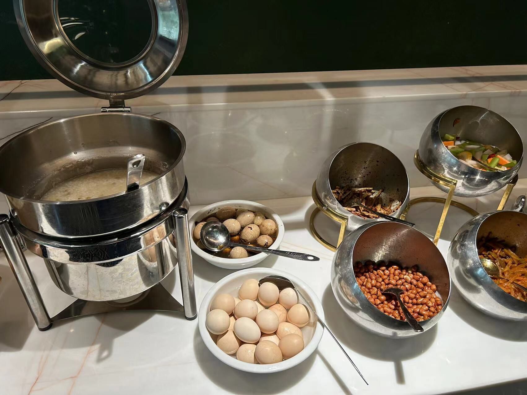 Disposição de buffet com diversos pratos, incluindo uma panela grande, recipientes com ovos e recipientes com feijão.