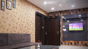 Um hall moderno com um sofá, uma mesa de centro de vidro, uma televisão na parede e uma porta com o número.