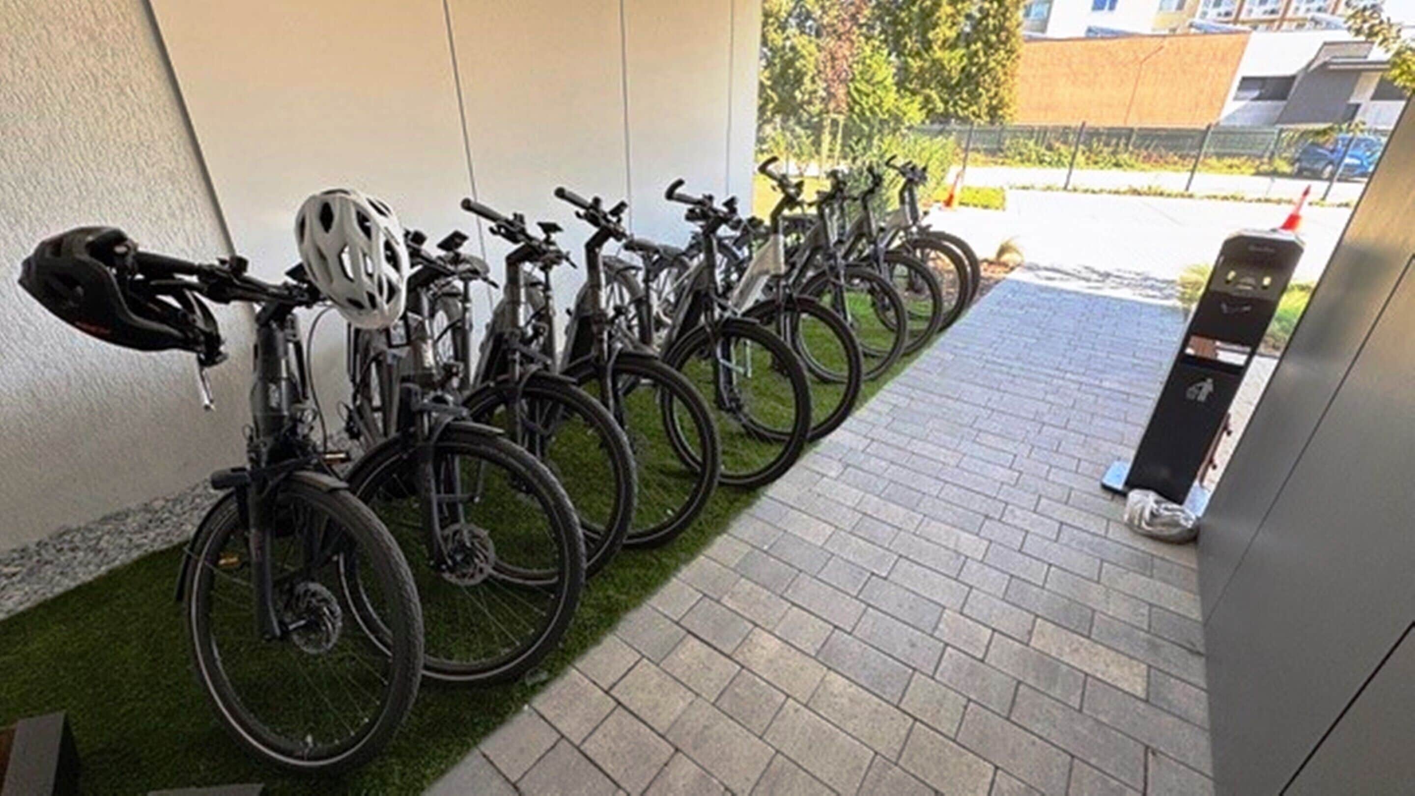 Uma fileira de bicicletas estacionadas junto a uma parede, com um caminho pavimentado na frente.