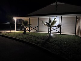 Um edifício moderno com um alpendre coberto, palmeiras e um gramado bem cuidado.