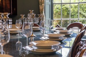 Uma mesa de jantar posta com pratos, copos e um candelabro de cristal.