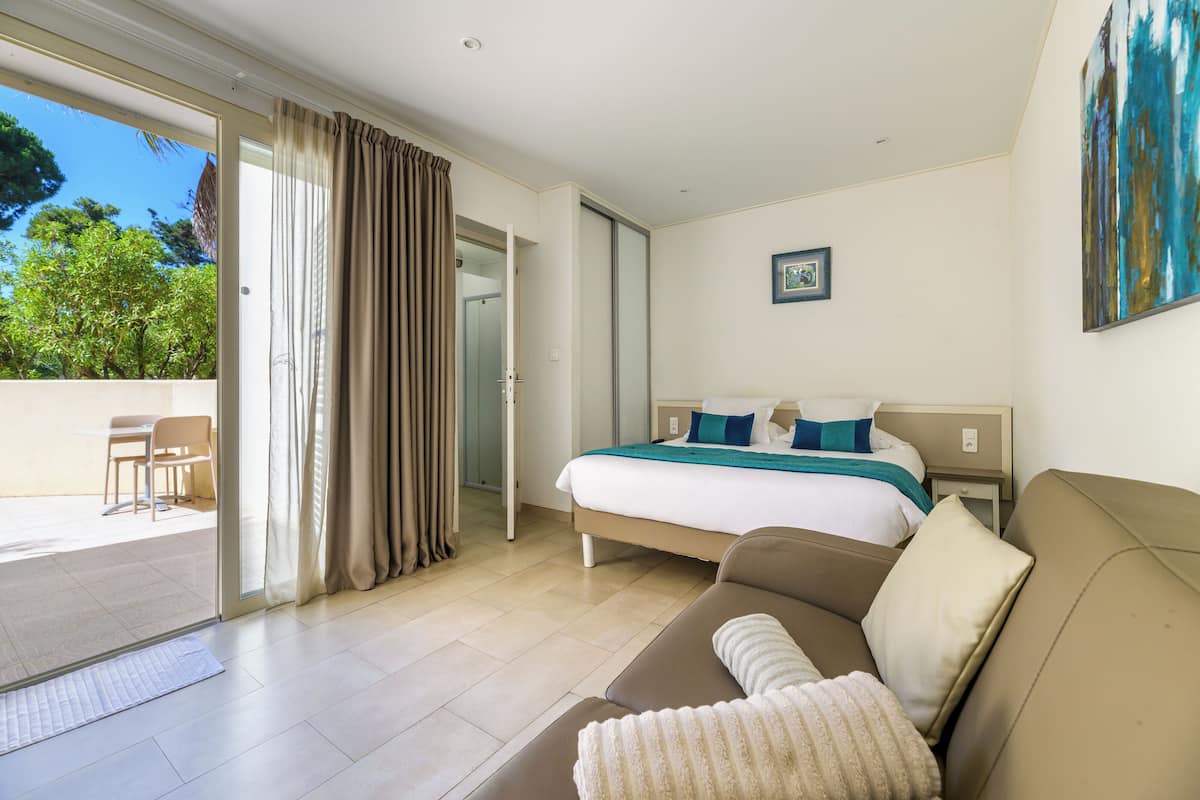 Quarto com cama, sofá, um quadro e vista para o exterior.