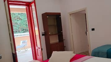 Quarto com cama, guarda-roupa e porta aberta para área externa.