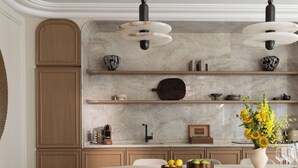 Cozinha moderna com armários de madeira, painel de fundo de mármore e área de refeições com mesa e cadeiras redondas.