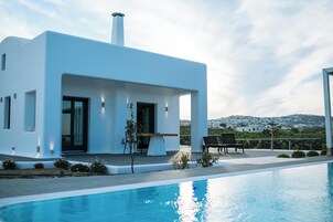 Um edifício moderno e branco com piscina, área de estar externa e vista para a paisagem.