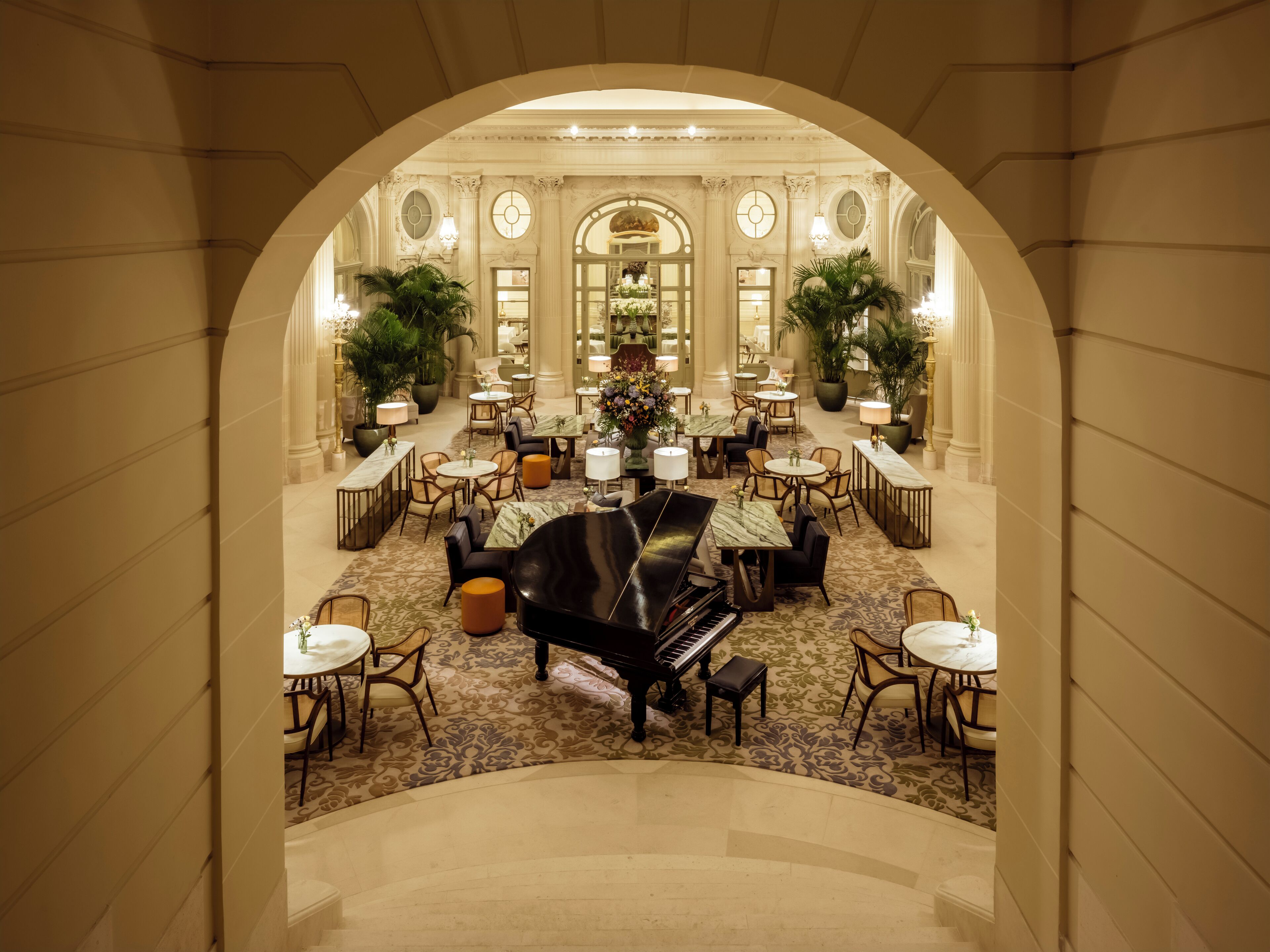 Um hall luxuoso com um piano de cauda, várias áreas de estar e decoração elegante.