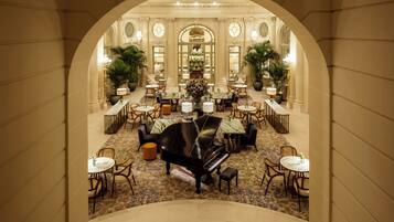 Um hall luxuoso com um piano de cauda, várias áreas de estar e decoração elegante.