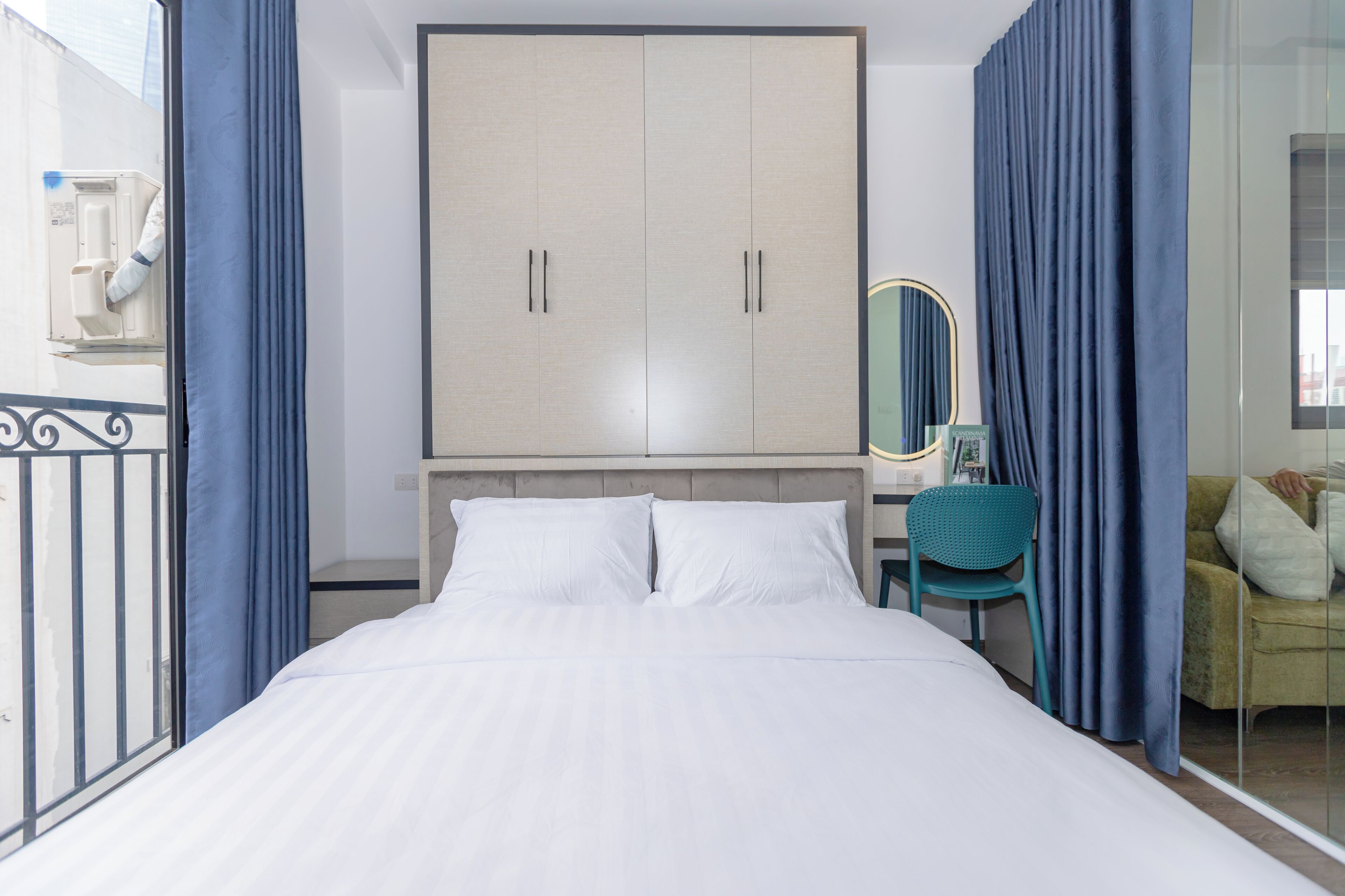 Quarto de hotel com uma cama grande, um guarda-roupa, uma escrivaninha com cadeira e um sofá.