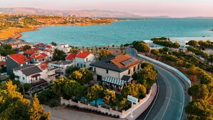 Uma área residencial costeira com casas, uma estrada sinuosa e vista para o mar.