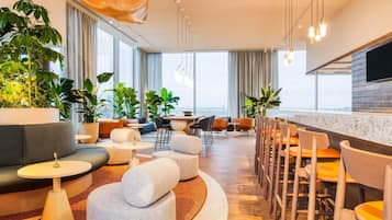 Uma área de estar moderna com assentos, um bar e amplas janelas com vista.