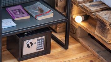 Piso de madeira, uma mesa de metal com livros e um cofre.