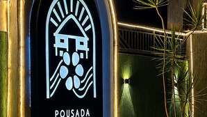 Um letreiro de neon com o desenho de uma casa e pegadas de pata, indicando que o estabelecimento aceita animais de estimação.