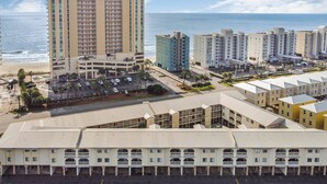 Um hotel à beira-mar com vários edifícios, estacionamento e vista para a praia.