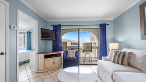 Quarto de hotel com cama, televisão, sofá, mesa de centro e varanda com vista.