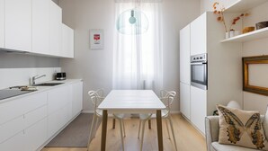 Uma cozinha moderna com armários brancos, uma mesa de jantar e um sofá.