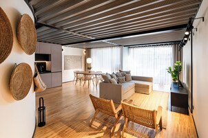 Uma sala de estar moderna com sofá, cadeiras, uma mesa de jantar e uma área de cozinha.