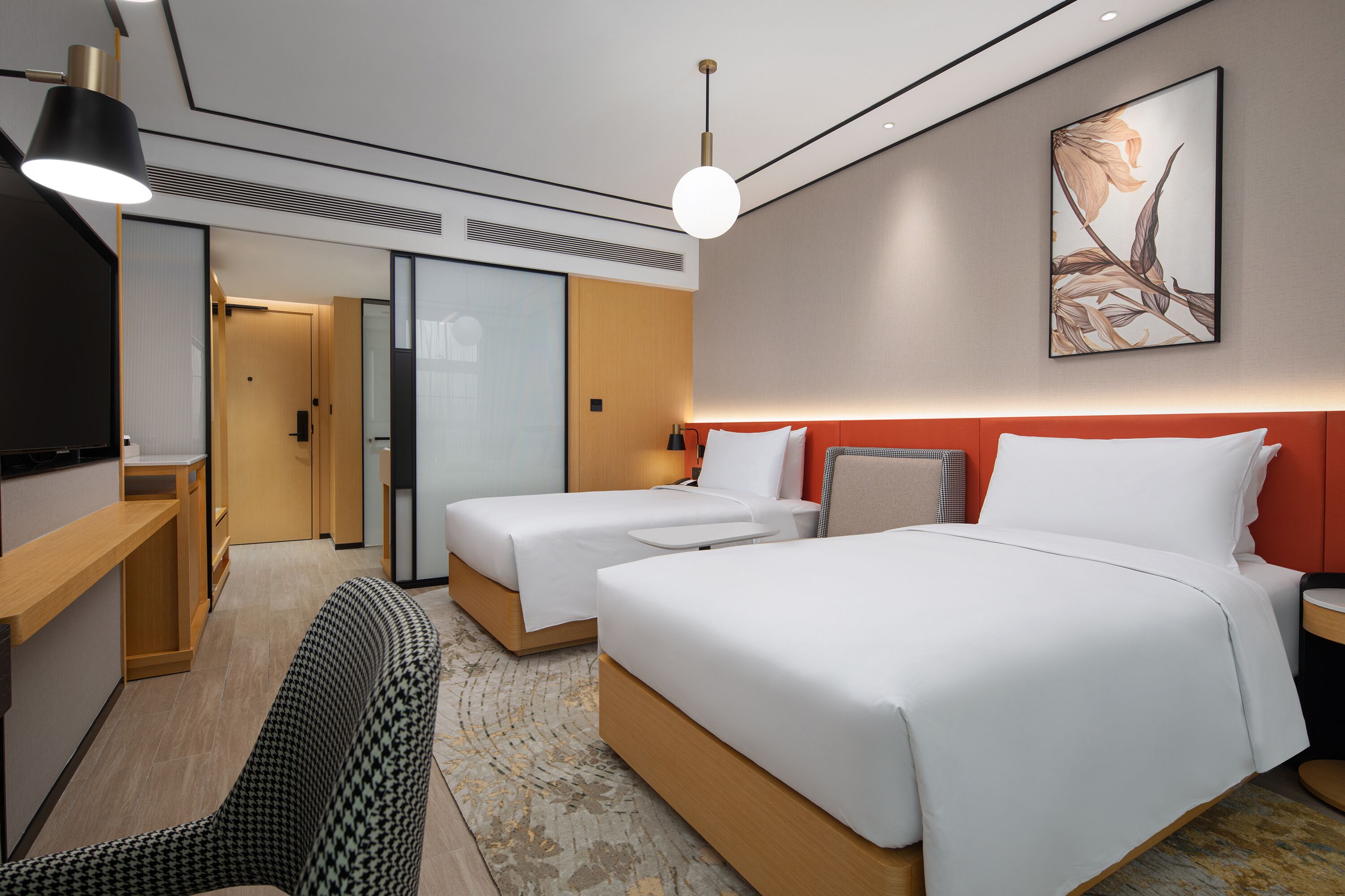 Quarto de hotel com duas camas, uma escrivaninha, uma cadeira e um quadro grande na parede.