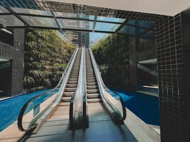 Área interna de piscina com uma escadaria rolante que leva a um andar superior.