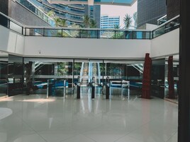 Um átrio amplo com um escadutor central, guarda-corpos de vidro e arquitetura moderna.