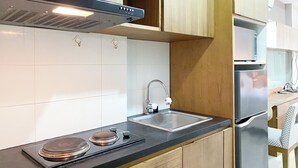 Uma cozinha moderna com exaustor preto, pia de aço inoxidável e armários de madeira.