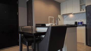 Apartamento Deluxe | Cozinha privada | Um frigorífico/congelador grande, uma placa de cozinha, mesas de jantar