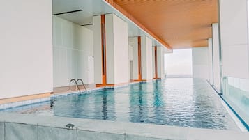Piscina interna com teto de madeira e paredes de vidro.