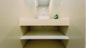Uma casa de banho moderna com uma pia branca, um espelho e uma planta num vaso.