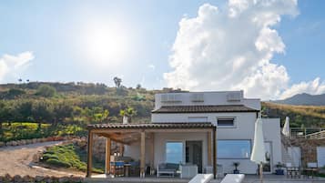Uma casa moderna com piscina, área de estar externa e vista para as colinas.