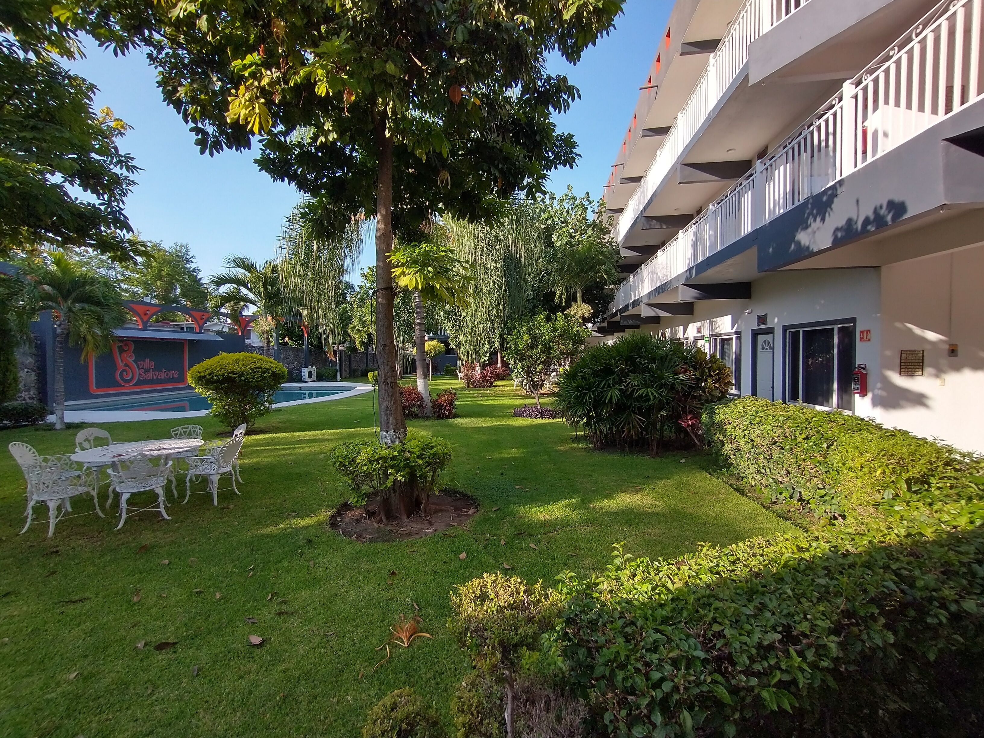 Um pátio com piscina, área de estar ao ar livre e um edifício com varandas.