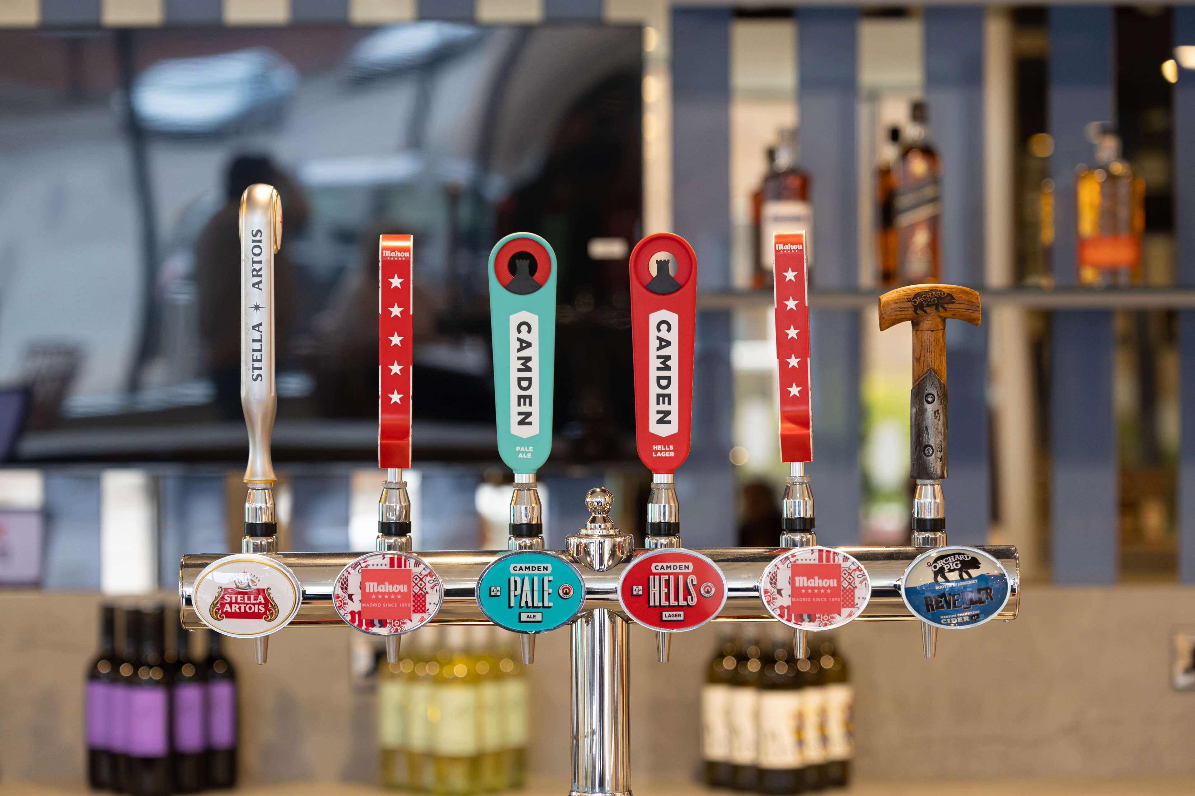 Sistema de torneiras com diversas opções de cerveja, incluindo marcas como Stella Artois, Mahou, Camden Pale Ale e Hells.