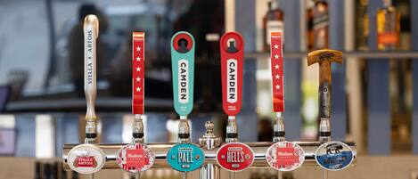 Sistema de torneiras com diversas opções de cerveja, incluindo marcas como Stella Artois, Mahou, Camden Pale Ale e Hells.
