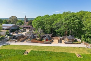 Um cenário rural com uma igreja, algumas cabanas pequenas e uma extensa área arborizada.