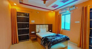 Quarto com cama, mesa de cabeceira, guarda-roupa e janela com cortinas.