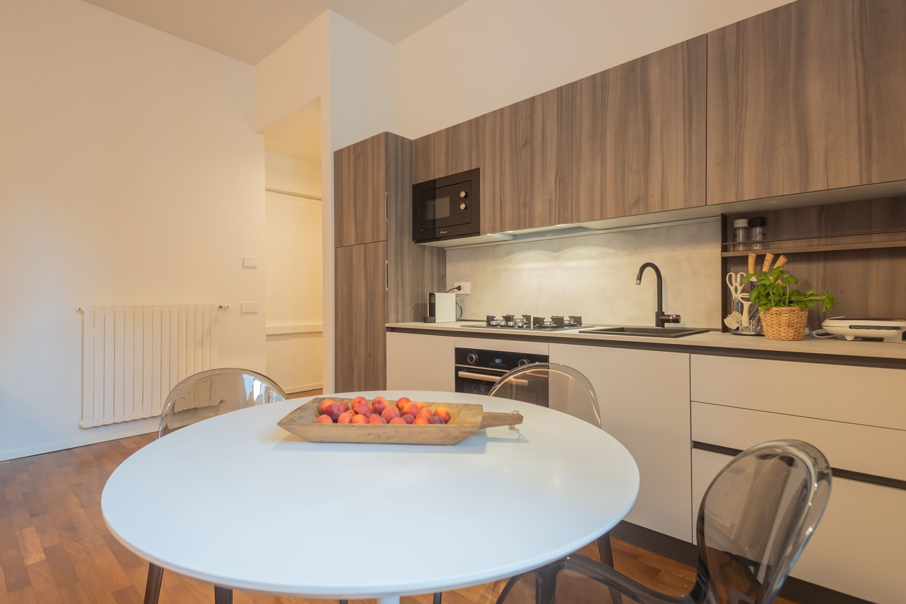 Uma cozinha moderna com uma mesa e cadeiras brancas, micro-ondas e pia.