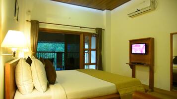 Quarto de hotel com cama, televisão, aparelho de ar condicionado e janela com cortinas.