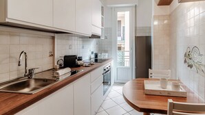 Uma cozinha moderna com armários brancos, bancada de madeira e um espaço de refeições com mesa e cadeiras.