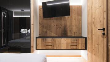 Quarto moderno com guarda-roupa de madeira, televisão de tela plana na parede e cama com roupa de cama branca.