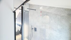 Um banheiro moderno com box de vidro, porta-toalhas e ladrilhos estampados.